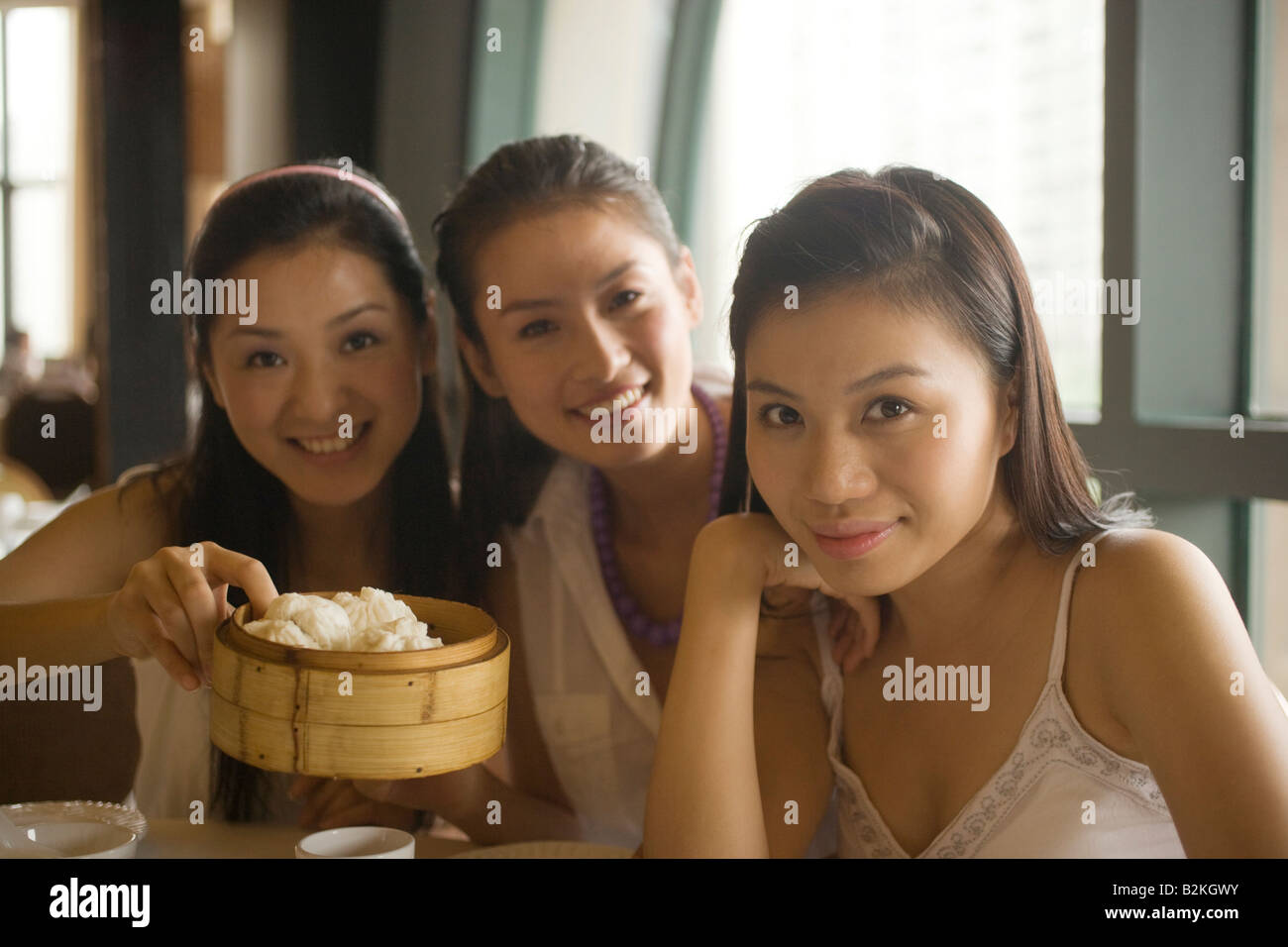 Portrait of three young women sitting at a table in a restaurant and ...
