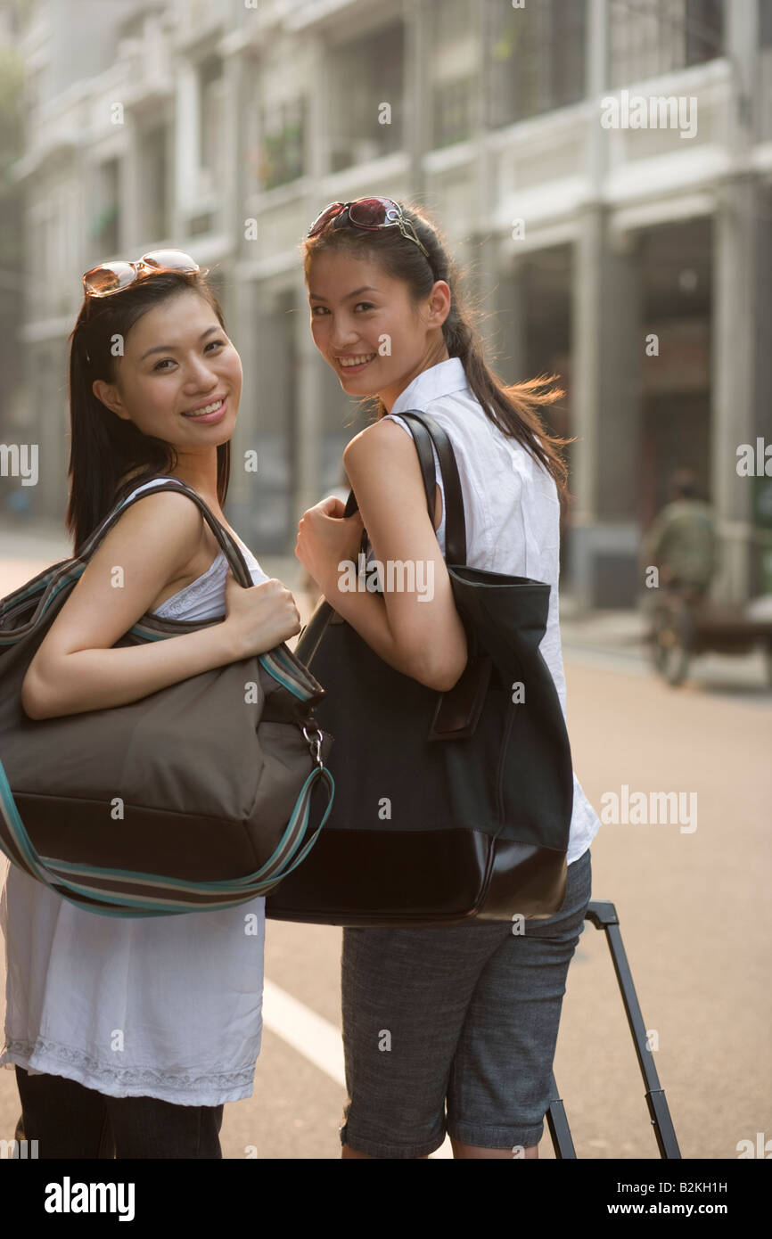 Portrait of two young women with their luggage and smiling Stock Photo ...