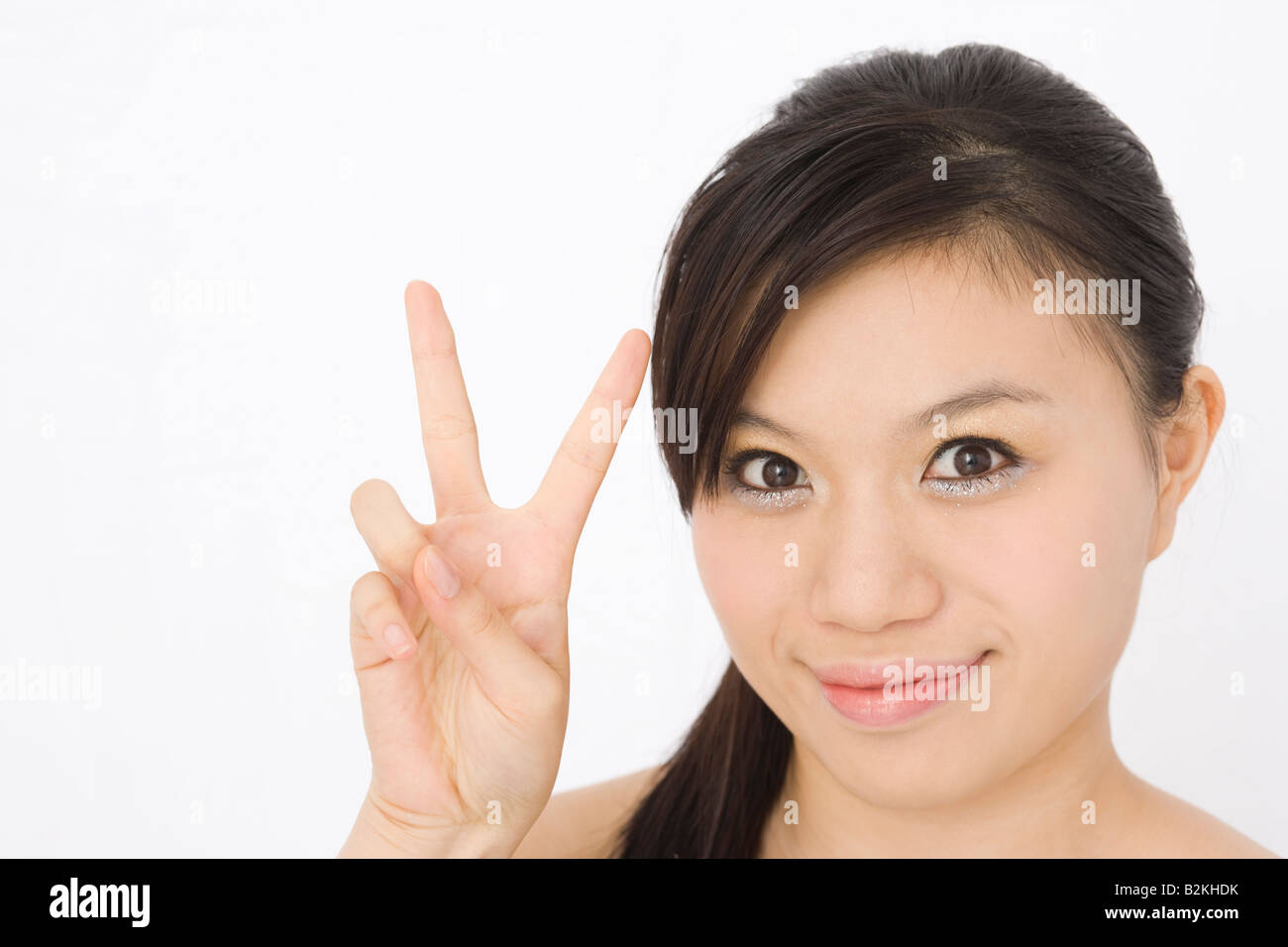 Portrait of a young woman showing peace sign Stock Photo - Alamy