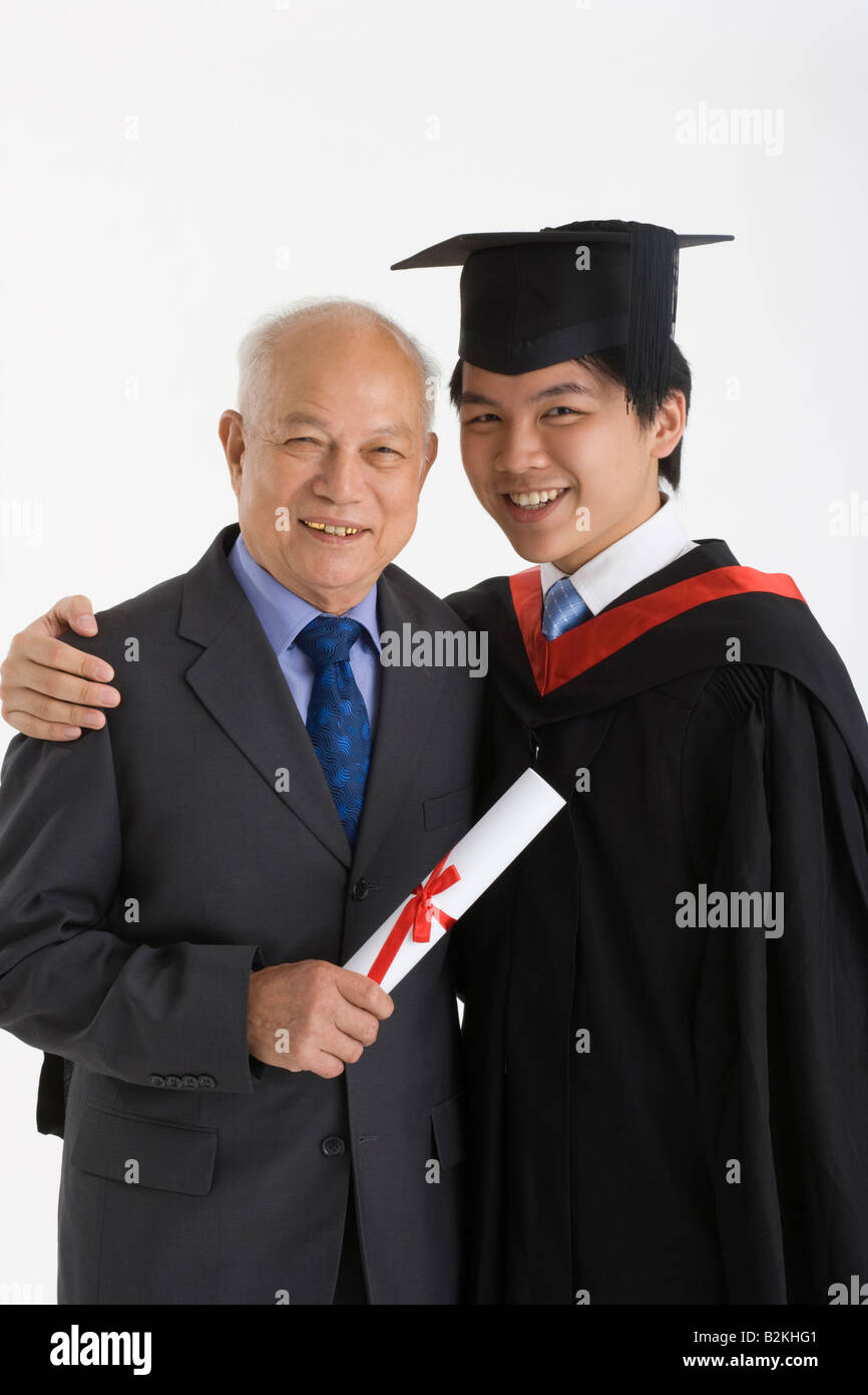 Portrait of a young male graduate standing with his father and smiling ...