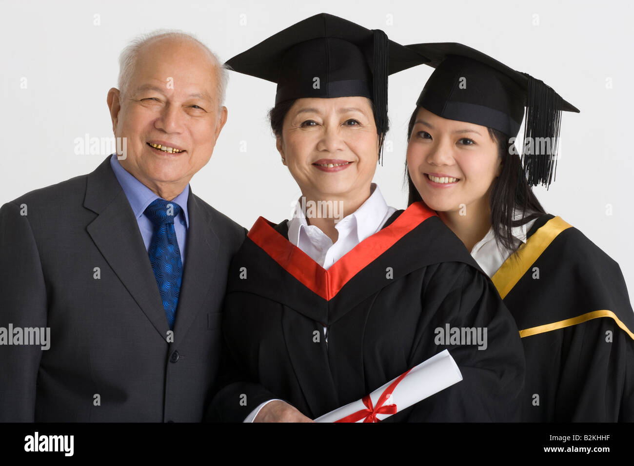 Portrait of a professor with his two female university students smiling ...