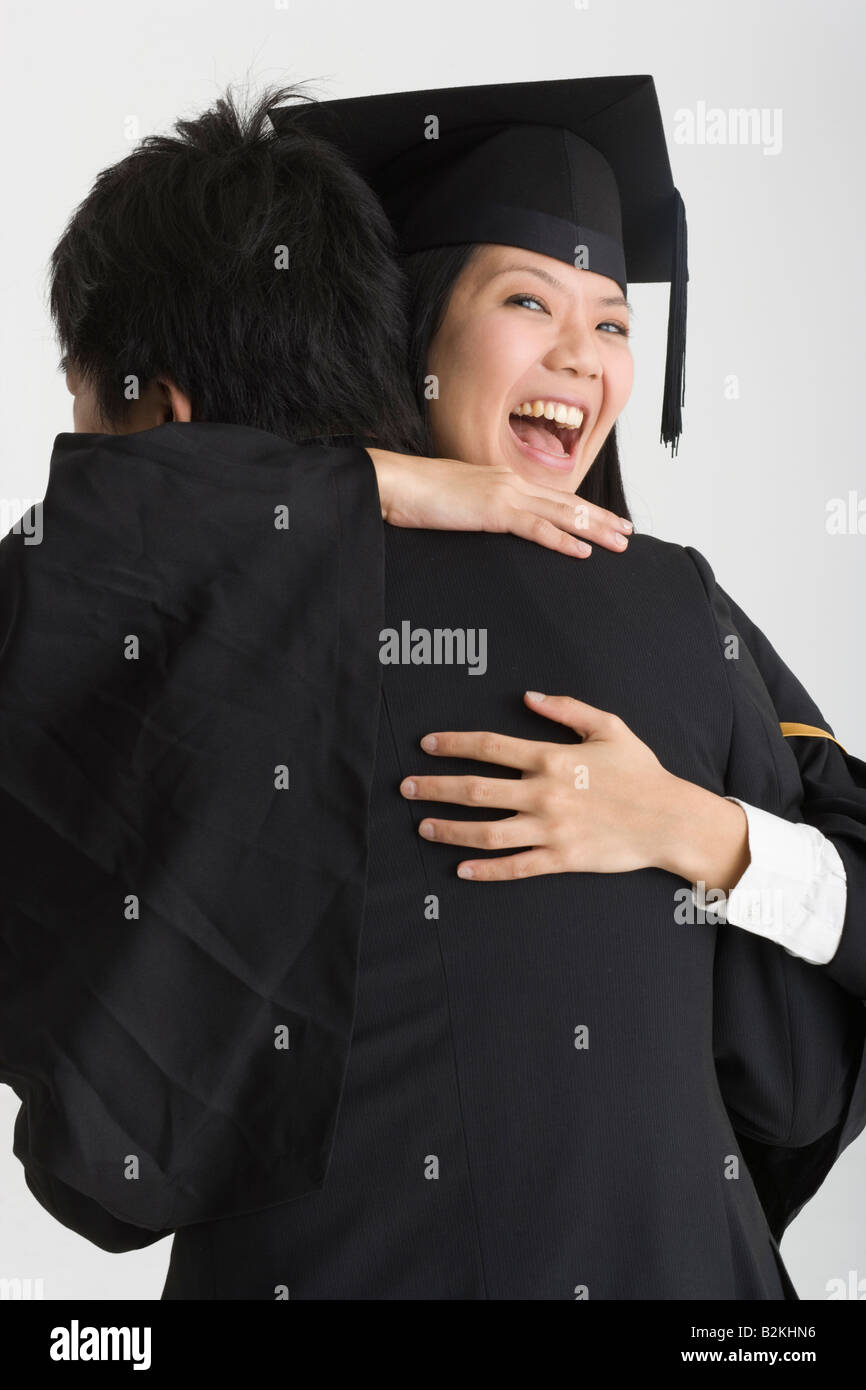 Portrait of a young female graduate hugging a young man and laughing ...