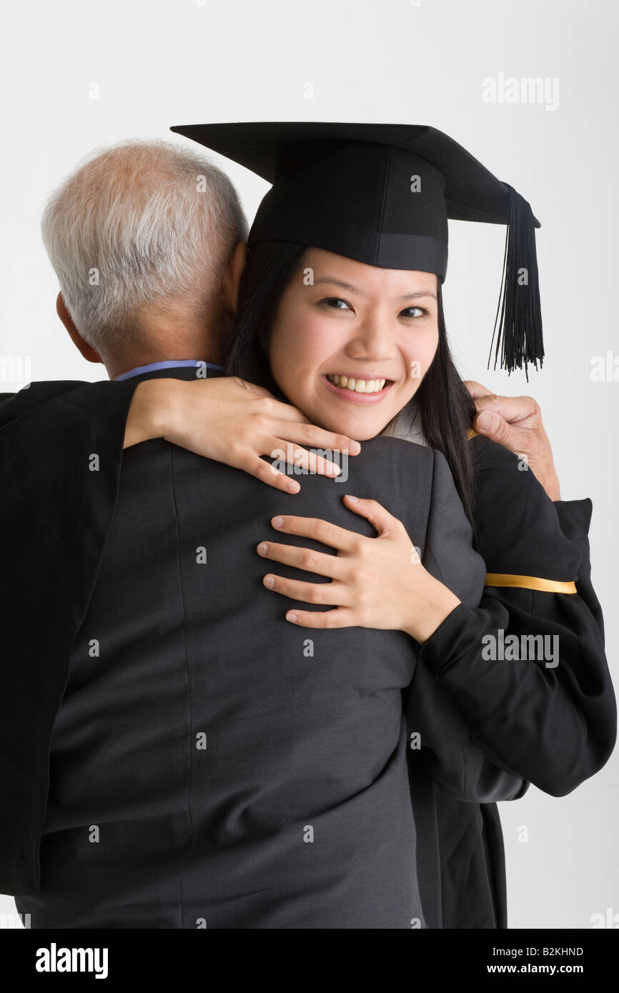 Portrait of a young female graduate hugging her father and smiling ...