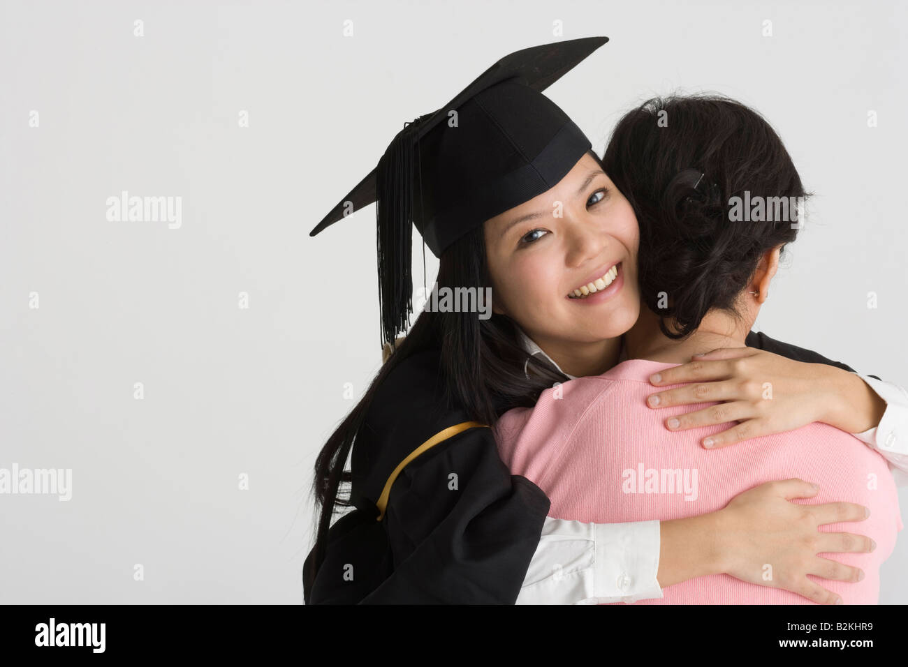 Portrait of a young female graduate hugging her mother and smiling ...