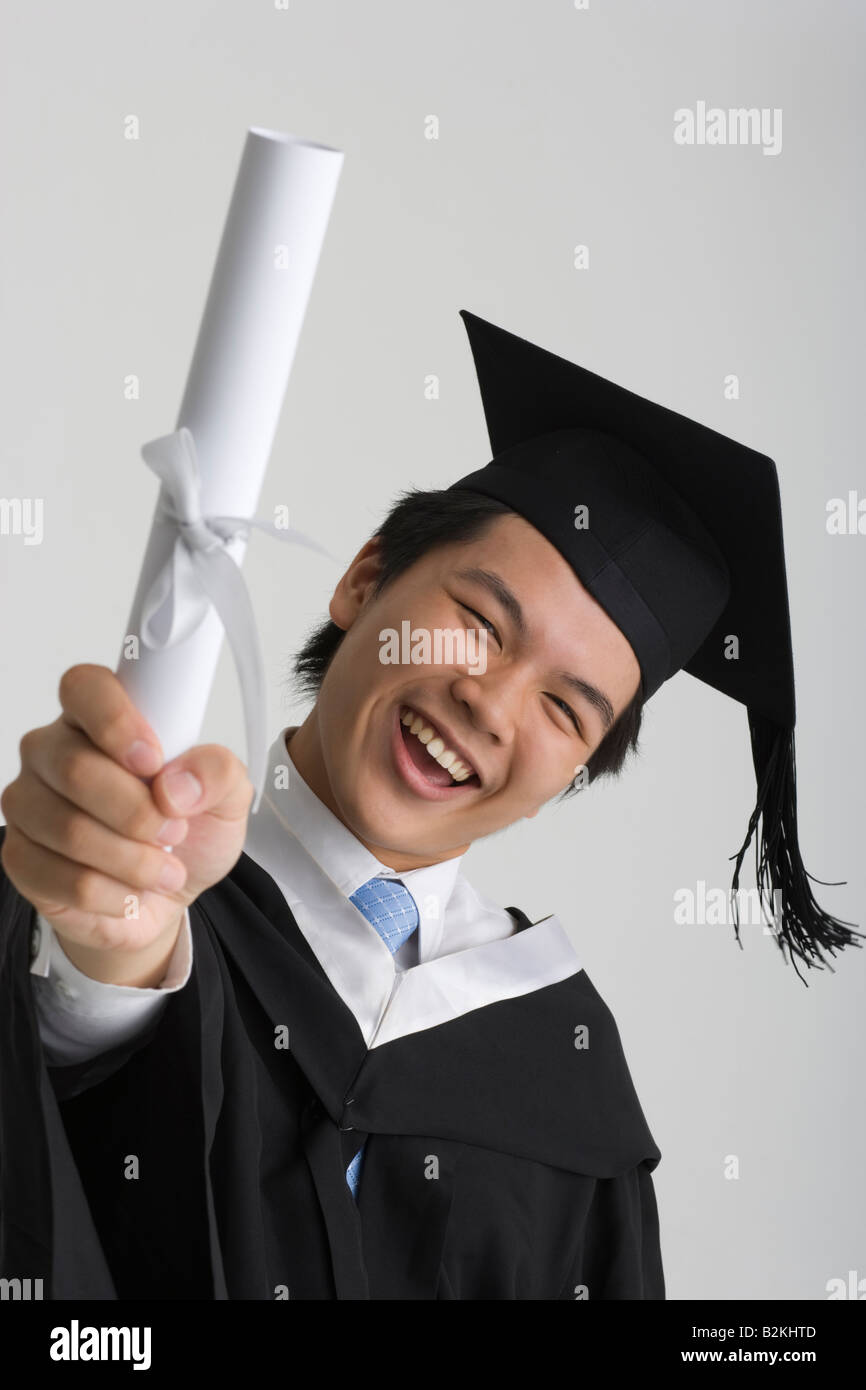 Portrait of a young male graduate showing a diploma and laughing Stock ...