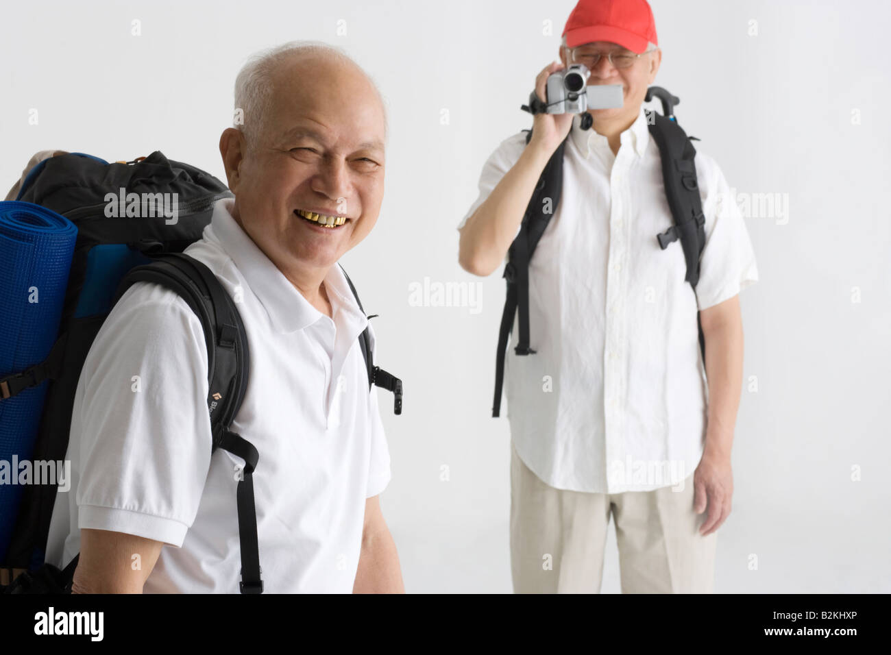 Portrait of a senior man smiling and his friend filming in the ...