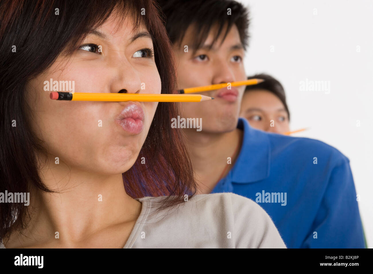 Three college students balancing pencils on their lips Stock Photo - Alamy