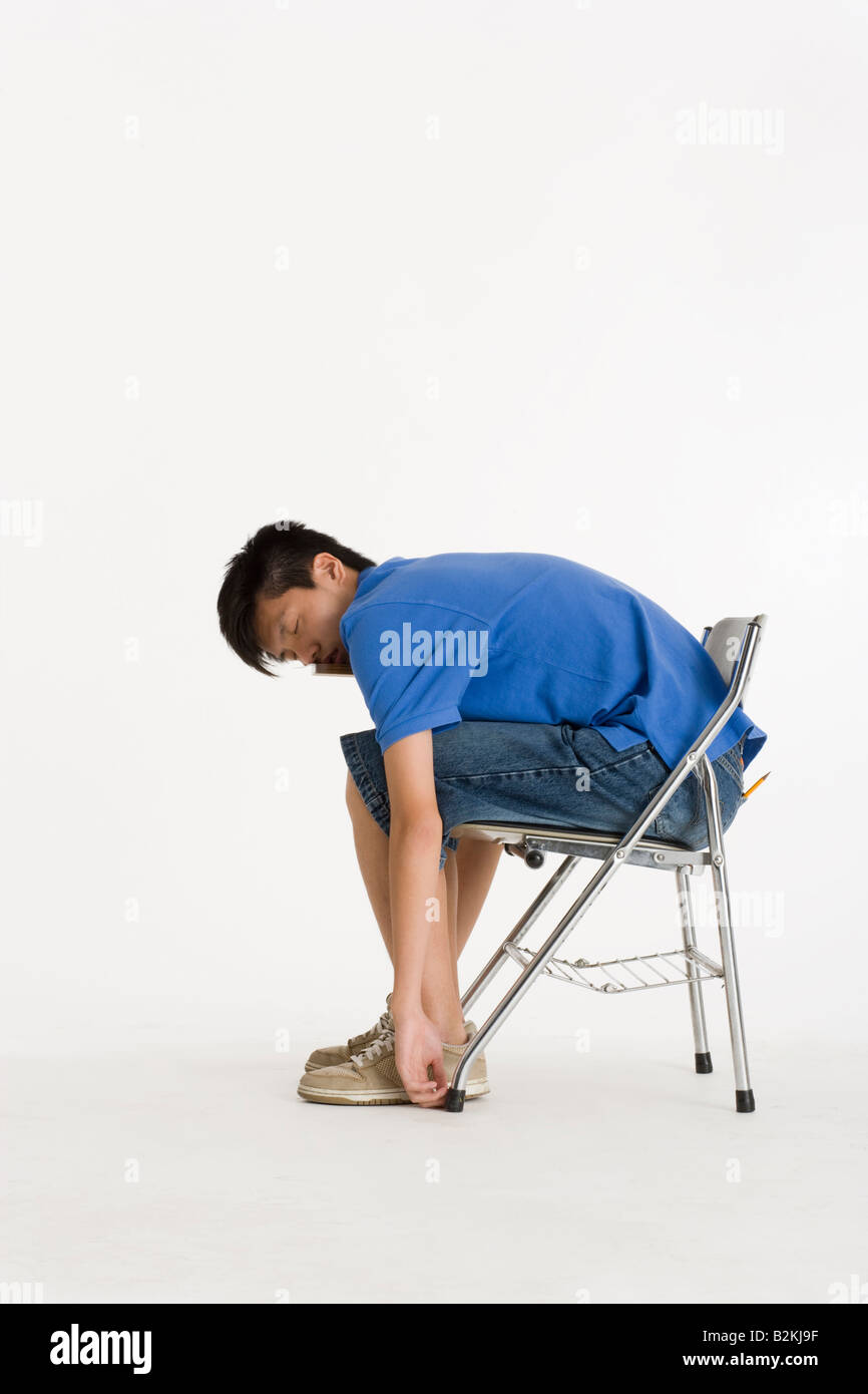 Young man napping on a writing chair Stock Photo - Alamy