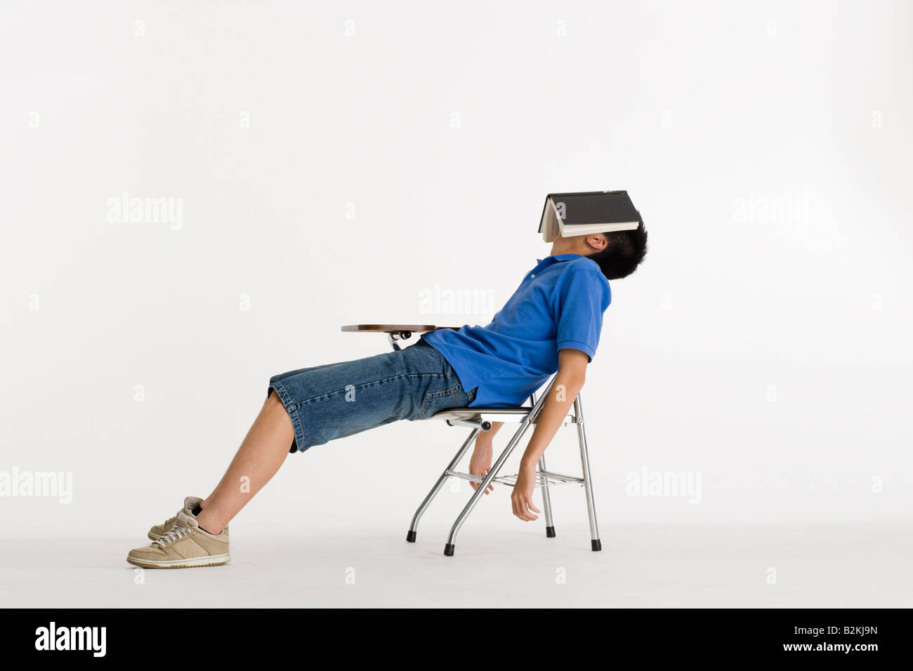 Young man napping on a writing chair Stock Photo - Alamy