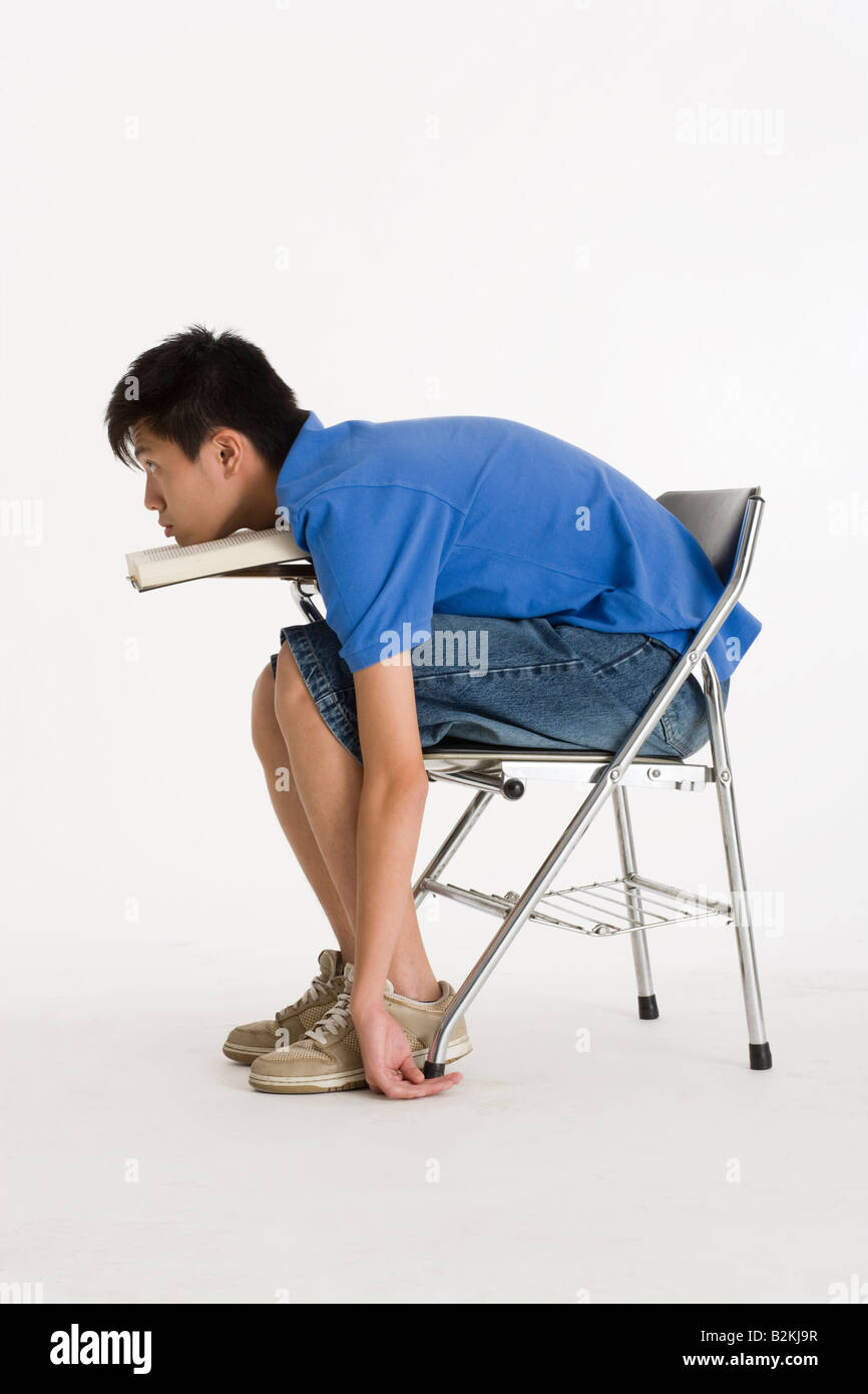Young man resting on a writing chair Stock Photo - Alamy
