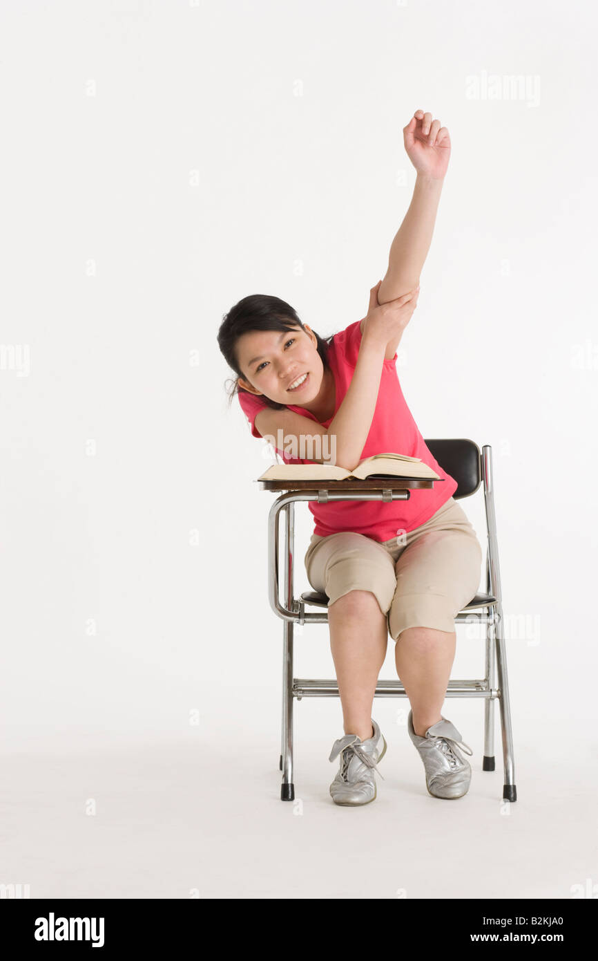 Portrait of a young woman sitting on a writing chair with her hand ...