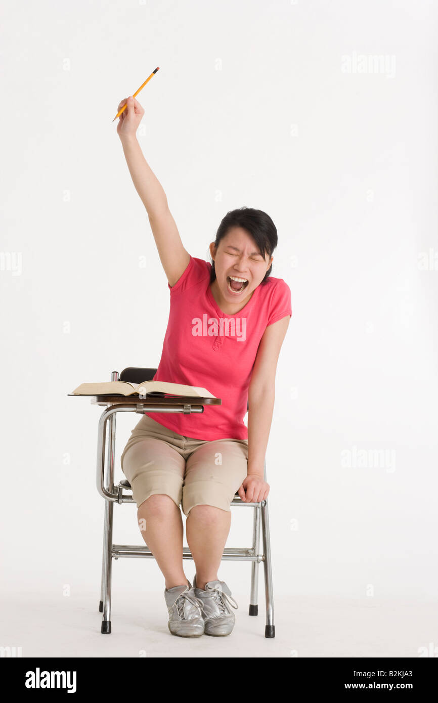 Young woman sitting on a writing chair with her hand raised Stock Photo ...