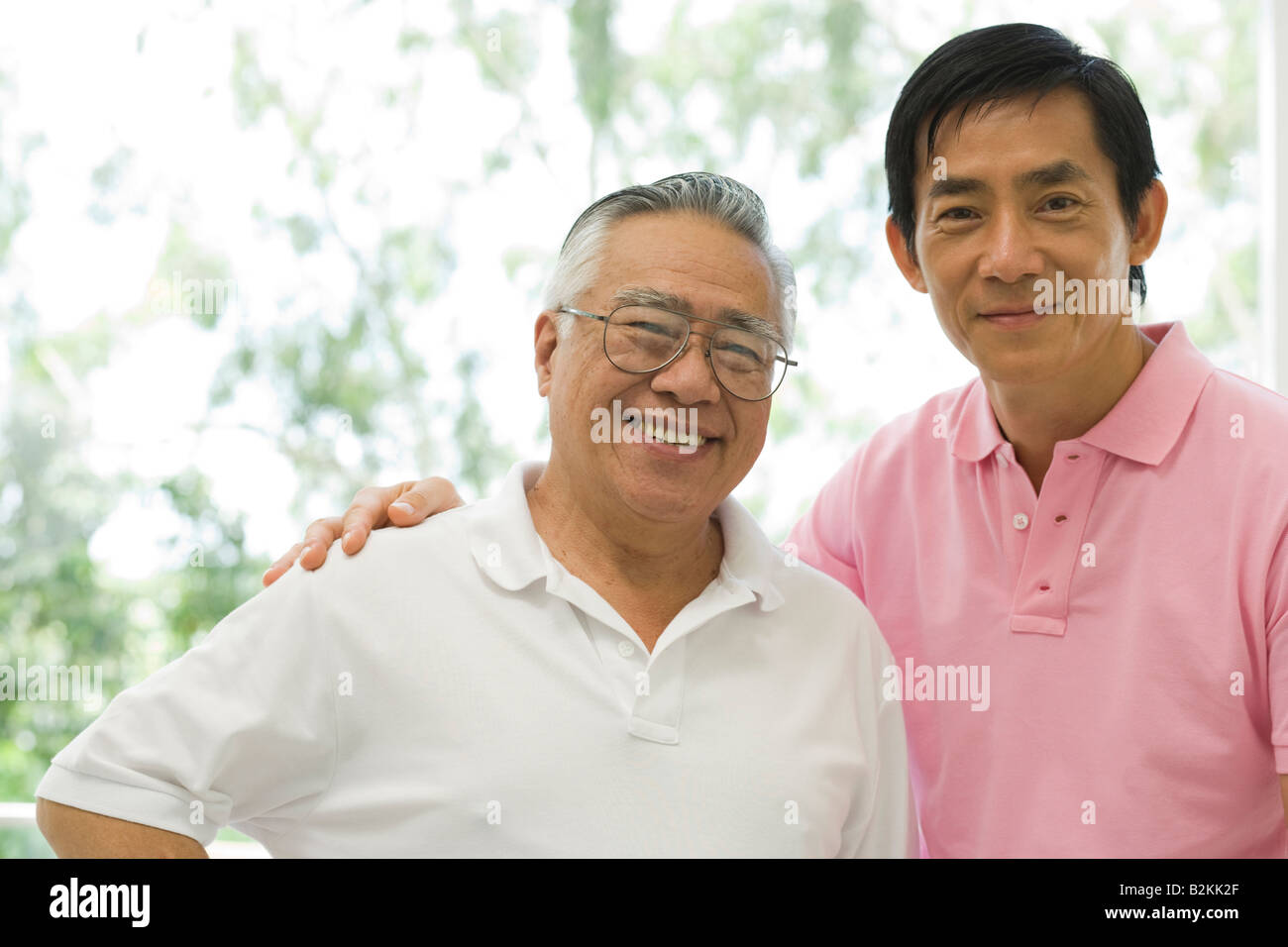 Portrait of a mid adult man smiling with arm around his father Stock ...