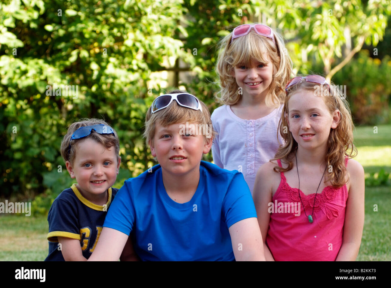 Group of four children pose for family picture in a garden Stock Photo ...