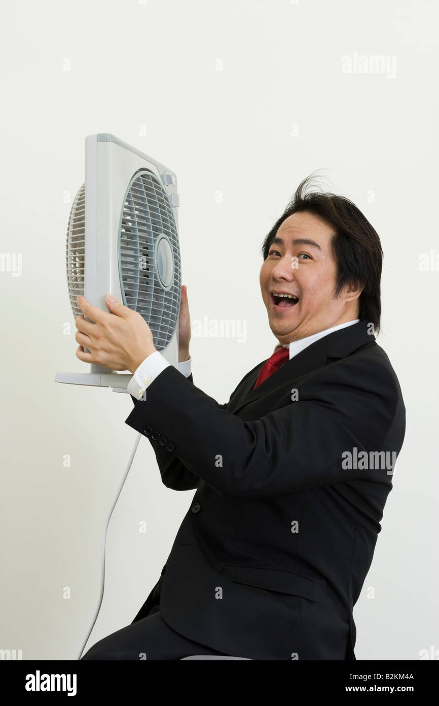 Portrait of a businessman holding an electric fan and laughing Stock ...