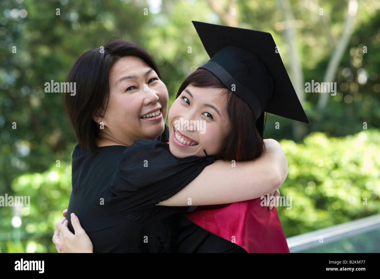 Portrait of a mid adult female graduate hugging her sister and smiling ...