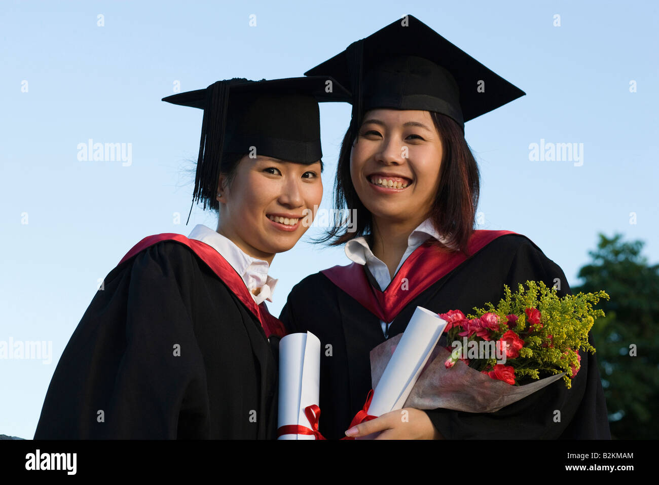 Portrait of two female graduates holding diplomas and smiling Stock ...