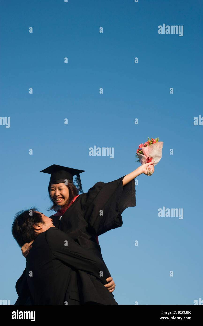 Low angle view of a mid adult man picking up a young female graduate ...