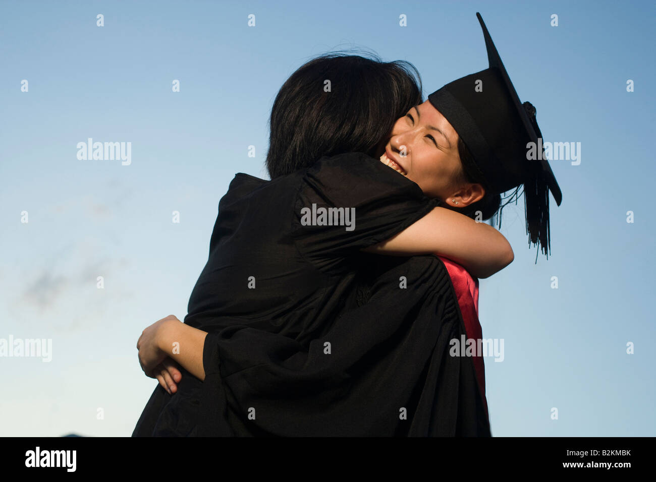 Side profile of a young female graduate hugging her sister Stock Photo ...