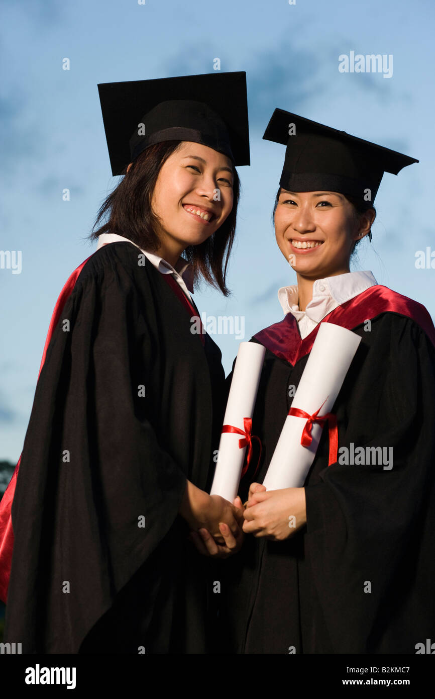 Portrait of two female graduates holding diplomas and smiling Stock ...