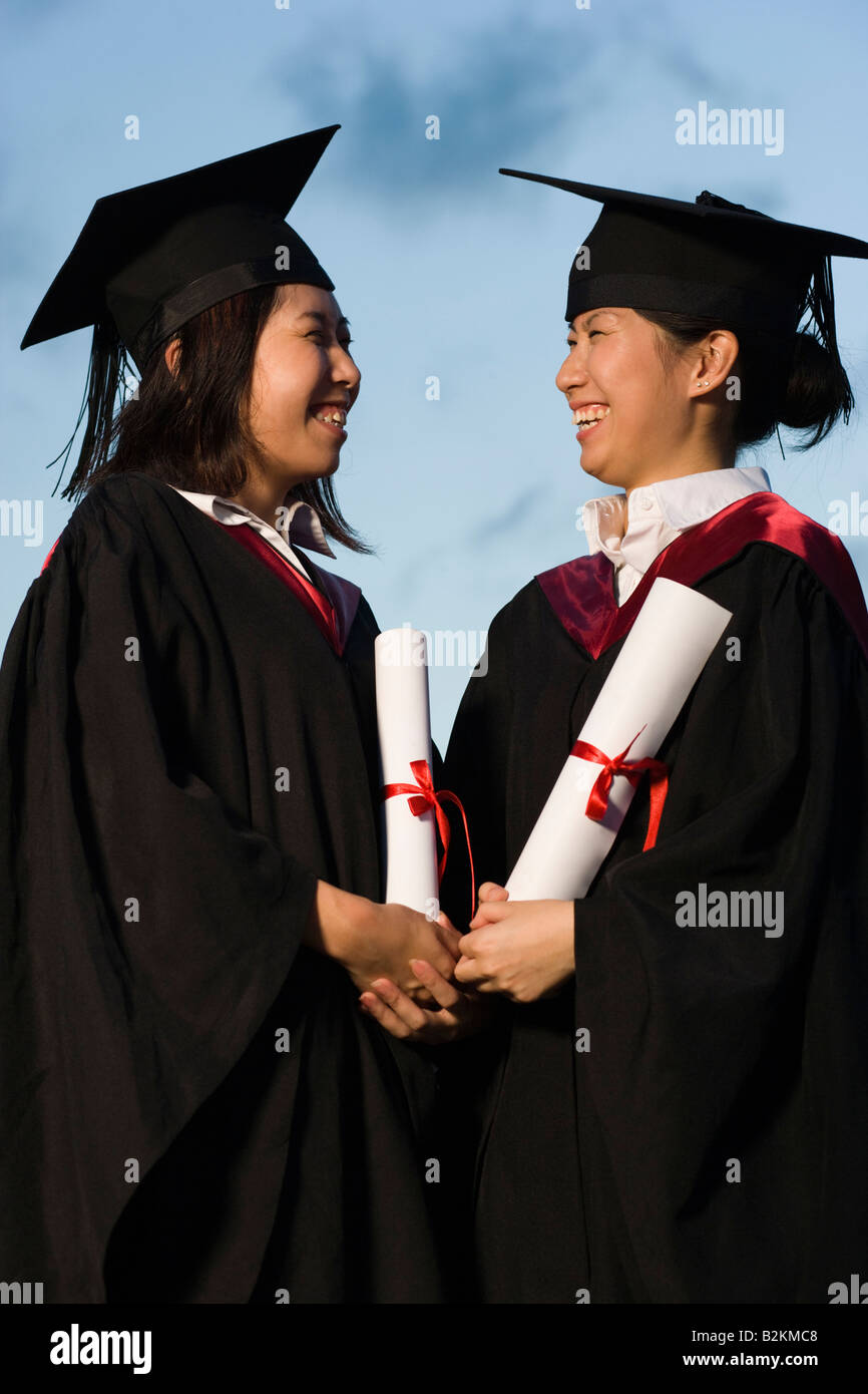 Two female graduates holding diplomas and smiling Stock Photo - Alamy
