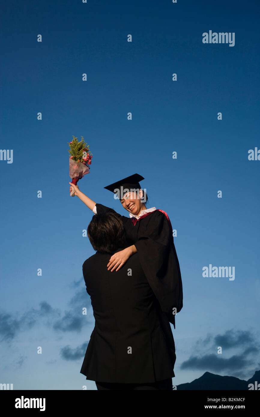 Low angle view of a mid adult man picking up a young female graduate ...