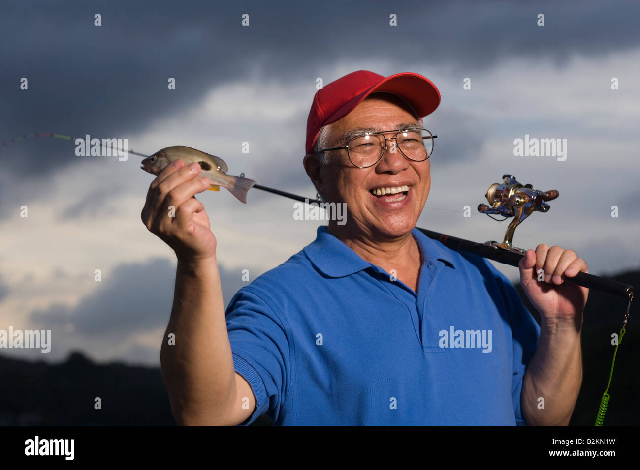 Portrait of a senior man holding a fish and smiling Stock Photo - Alamy