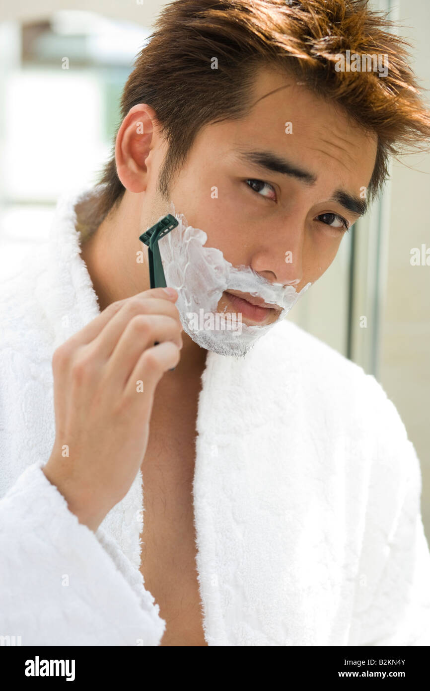 Portrait of a young man shaving with a razor Stock Photo - Alamy
