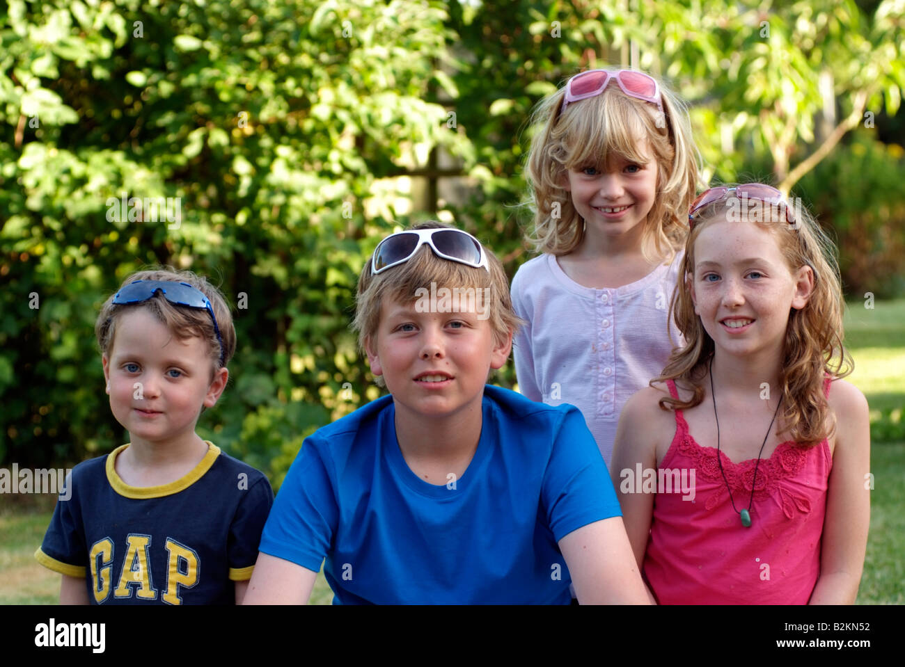 Group of four children pose for family picture in a garden Stock Photo ...