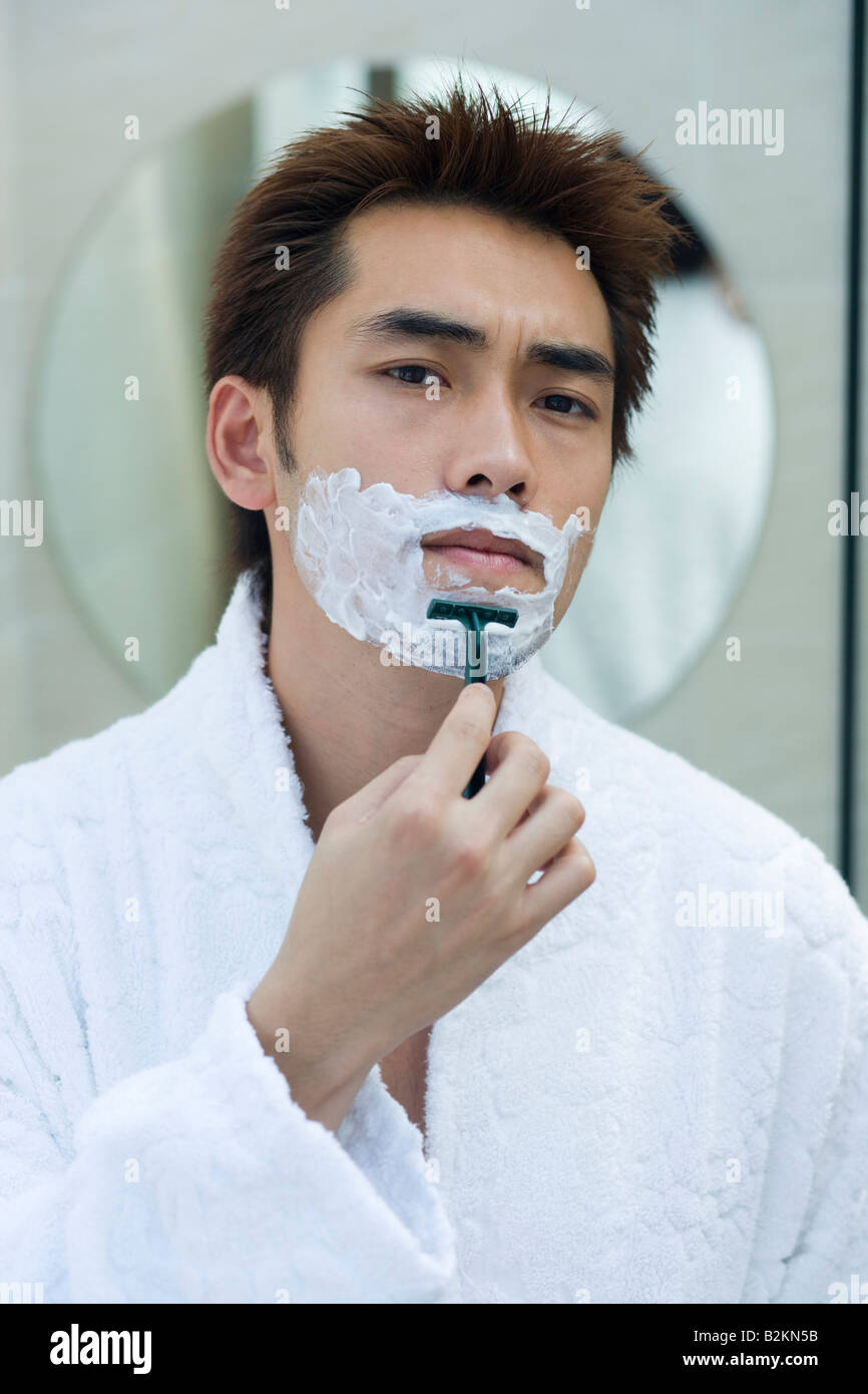 Portrait of a young man shaving with a razor Stock Photo - Alamy