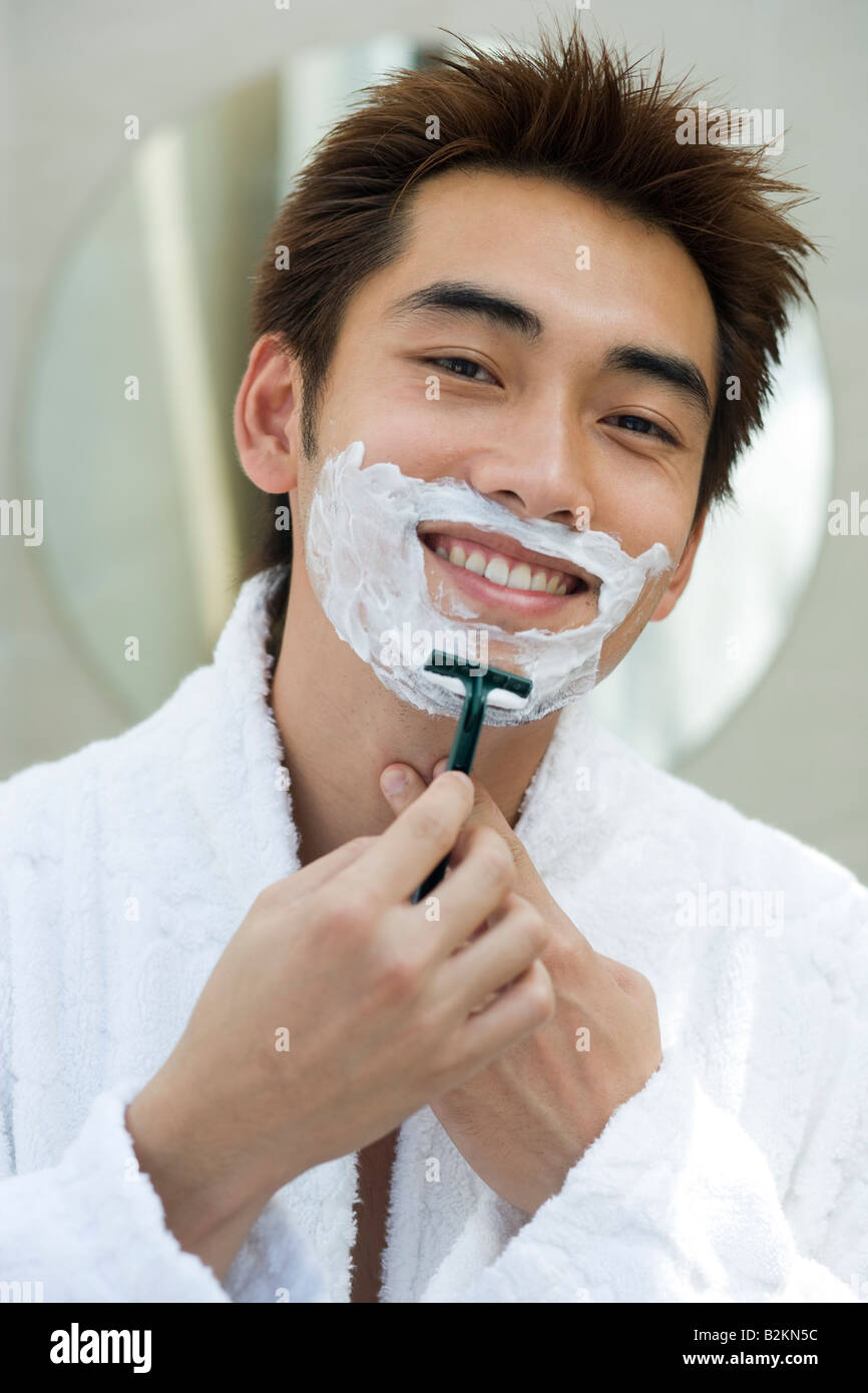 Portrait of a young man shaving with a razor and smiling Stock Photo ...