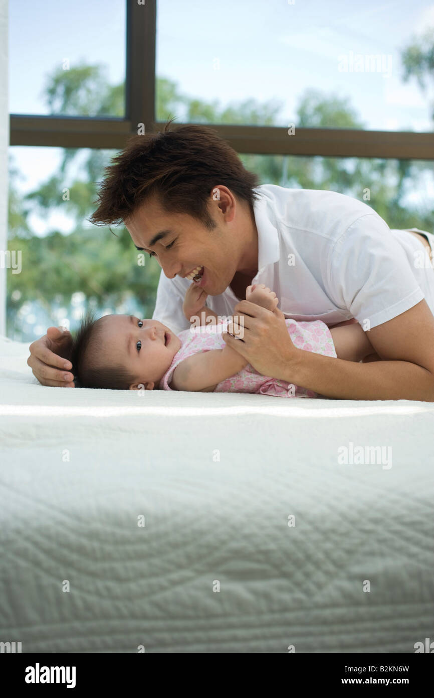 Young man cuddling with his daughter on the bed Stock Photo - Alamy