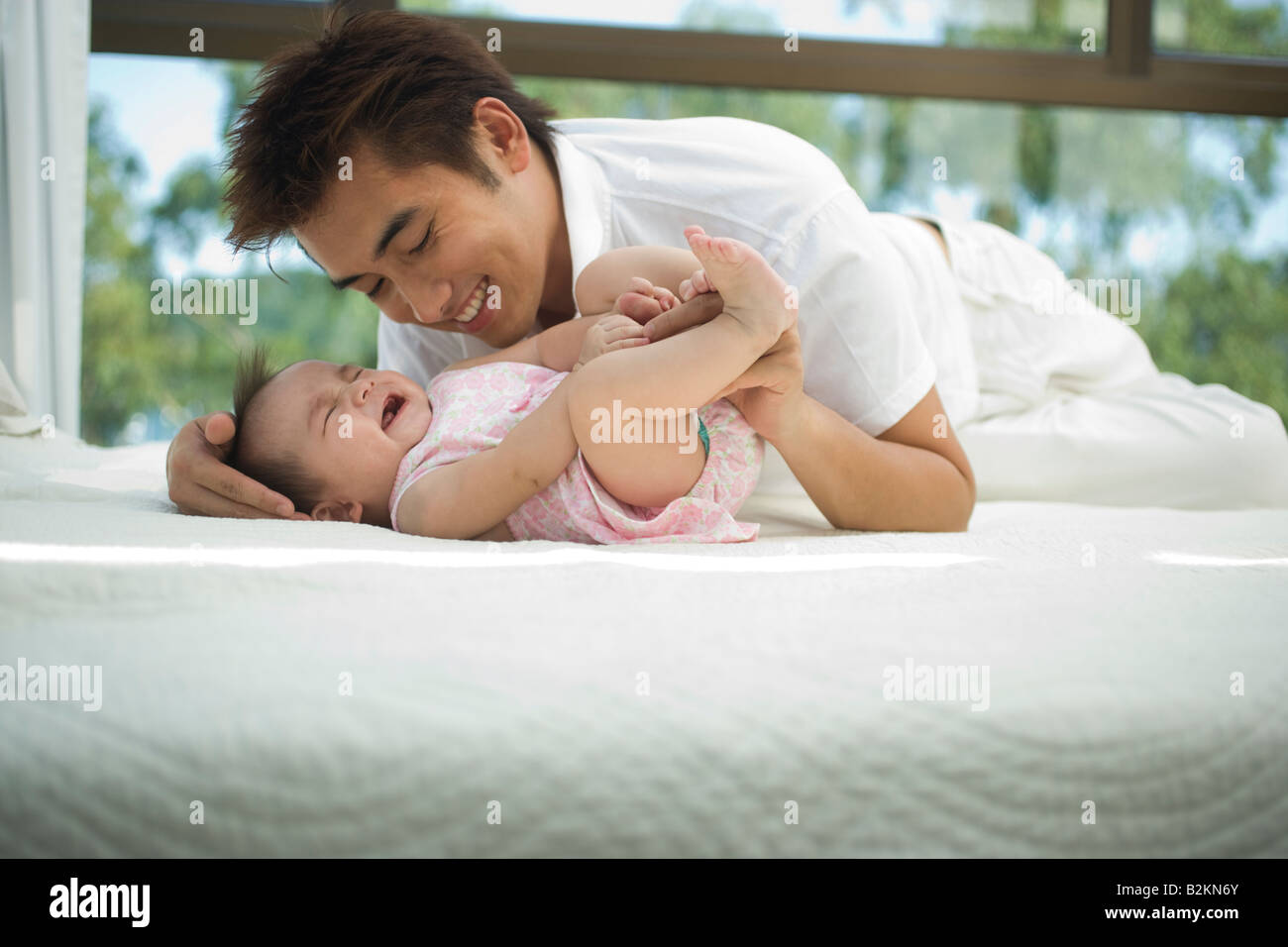 Young man cuddling with his daughter on the bed and smiling Stock Photo ...