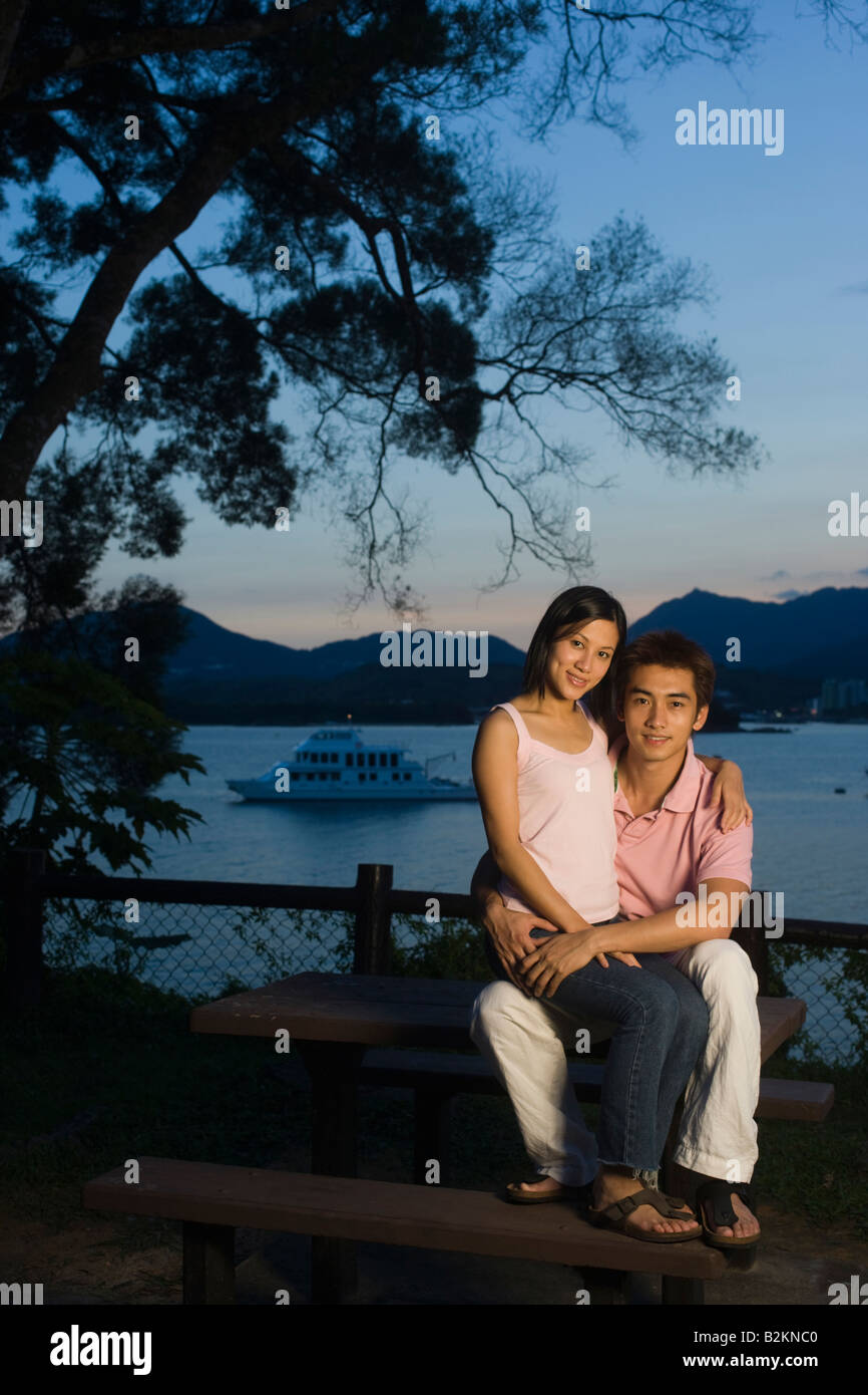 Portrait of a mid adult woman sitting on lap of a young man at the ...