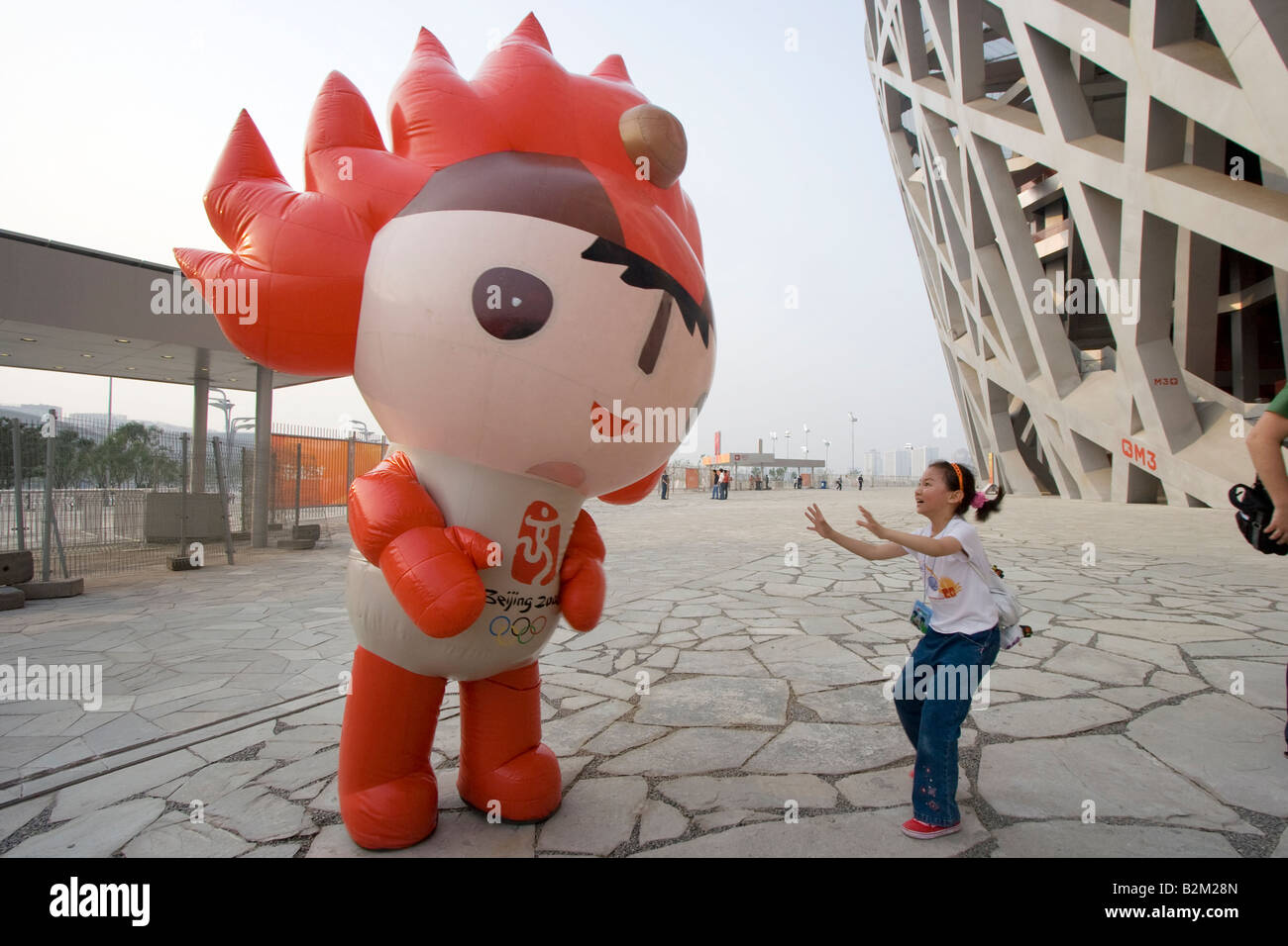 Huanhuan Olympic mascot and a happy surprised girl in front of the Bird ...
