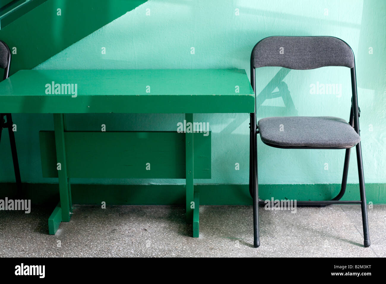 A folding chair and green table in a waiting room Stock Photo - Alamy