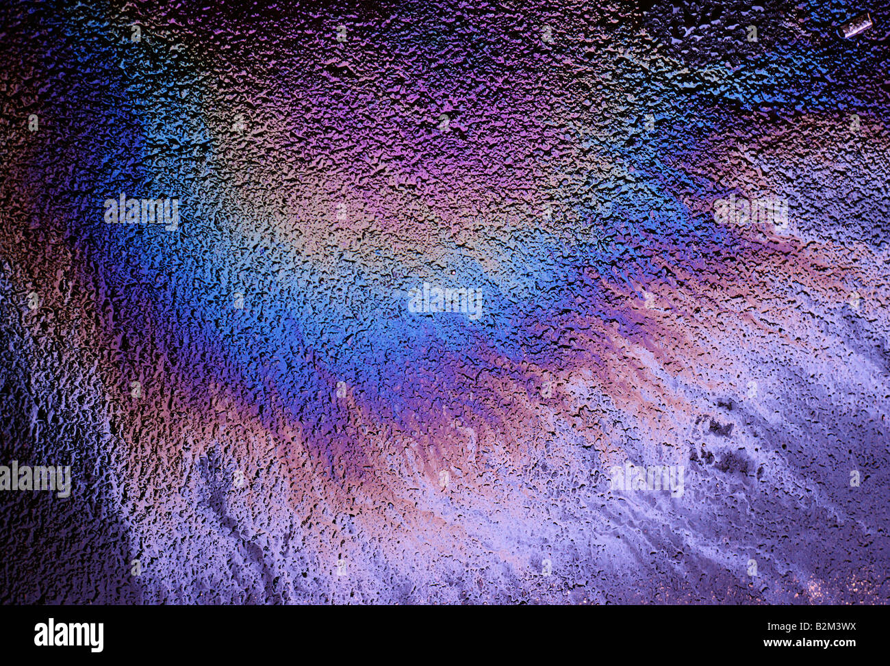 Close up view of motor oil on wet pavement Stock Photo - Alamy