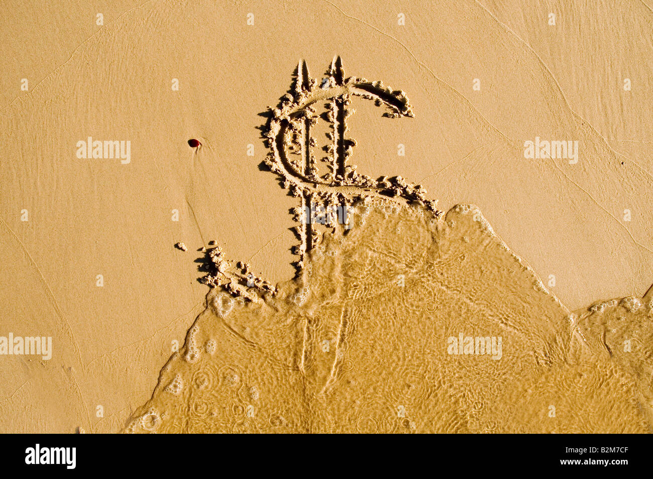 Sea washing off a dollar sign drawn in the sand Stock Photo - Alamy