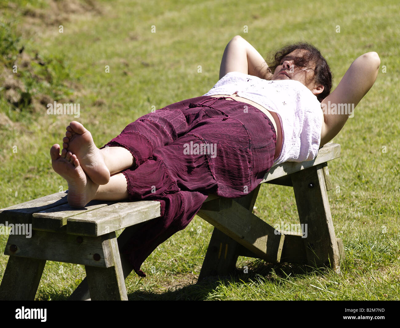 Woman asleep on a park bench in the afternoon sun Stock Photo - Alamy