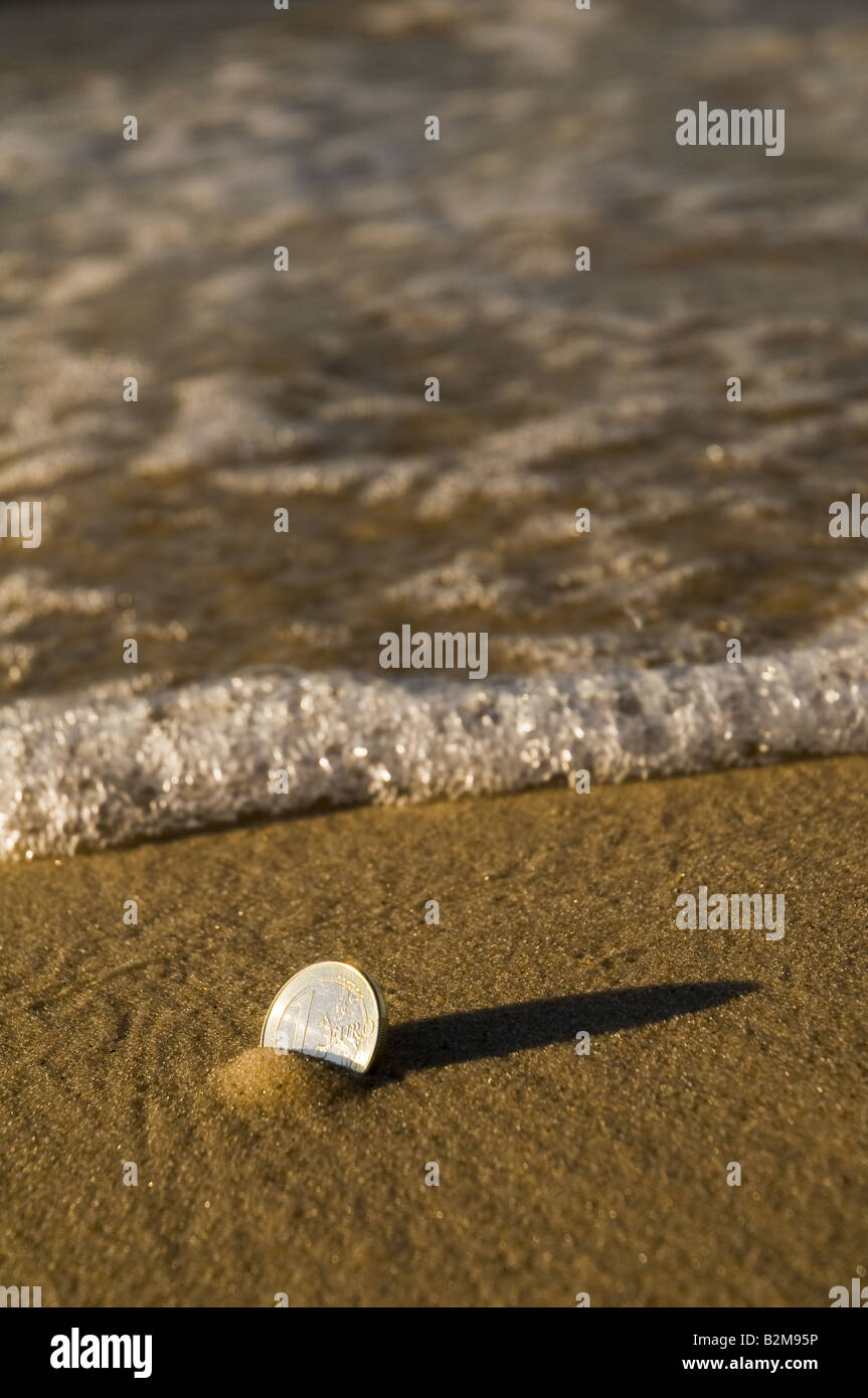 Euro coin in the sand on the beach Stock Photo - Alamy