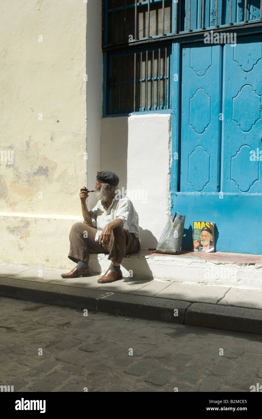 Seated man smoking pipe in the old town area of Havana, Cuba Stock ...