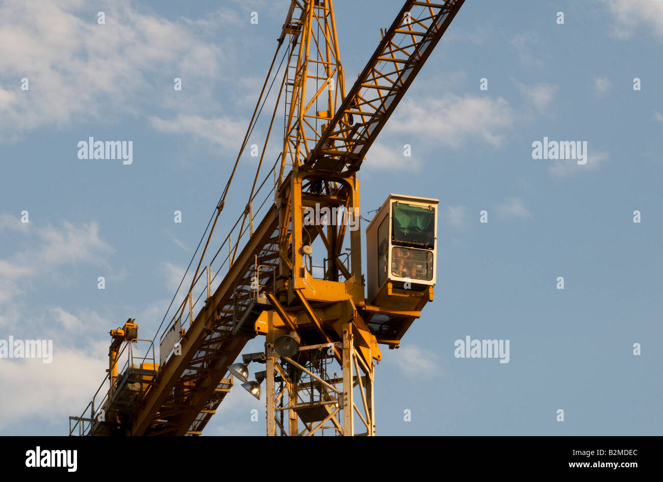 Yellow crane against a blue sky, crane operator visible in cab Stock ...