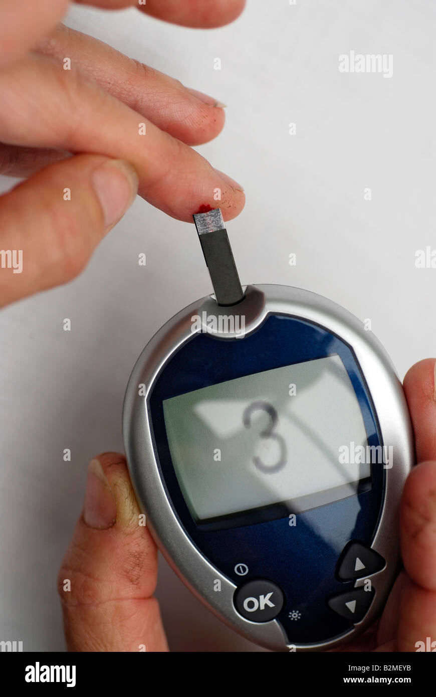 Diabetic applying blood sample to test strip in glucose meter Stock ...