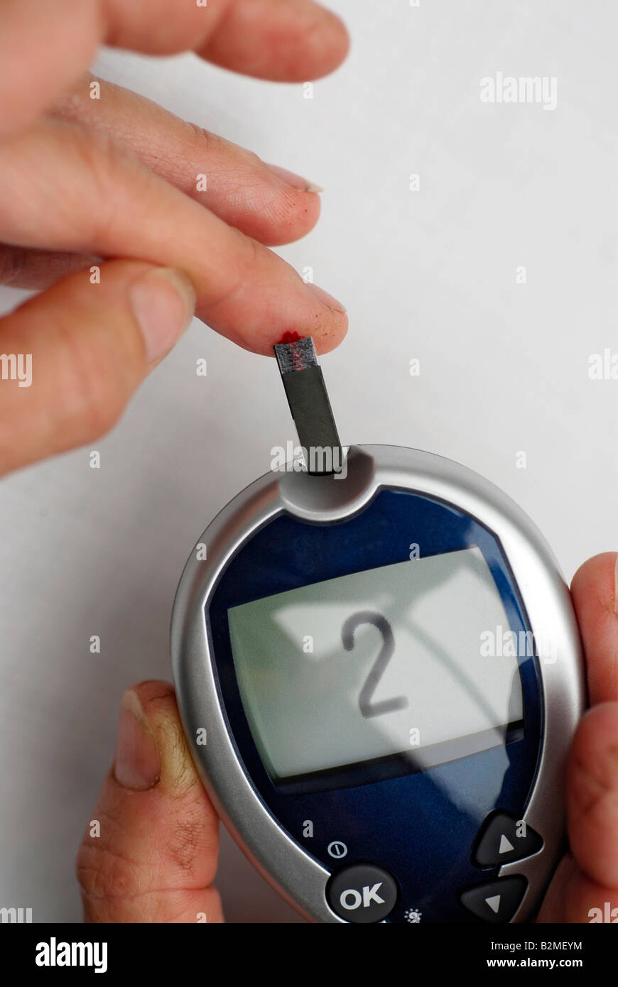 Diabetic applying blood sample to test strip in glucose meter Stock ...