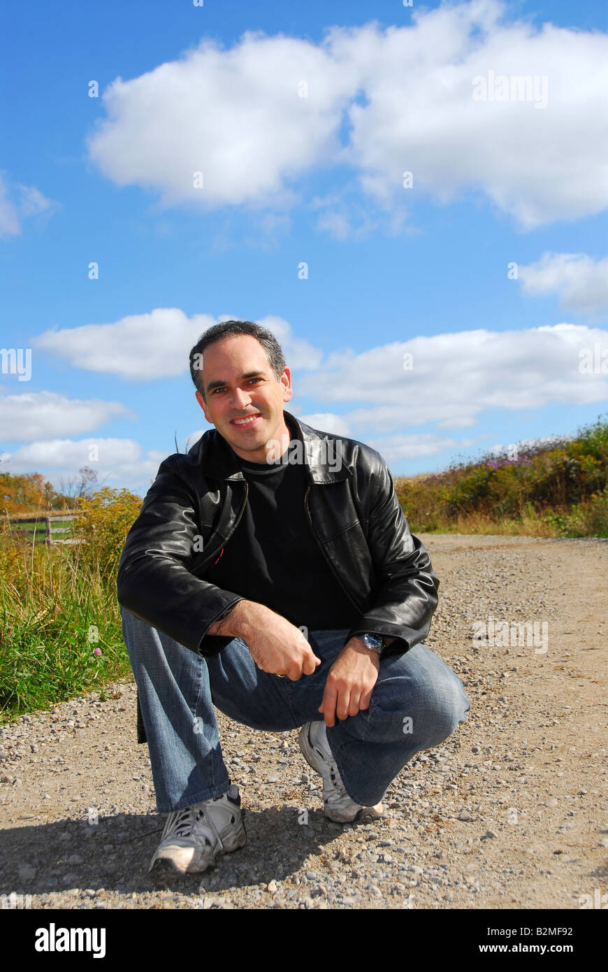 Smiling man sitting on a country road Stock Photo - Alamy