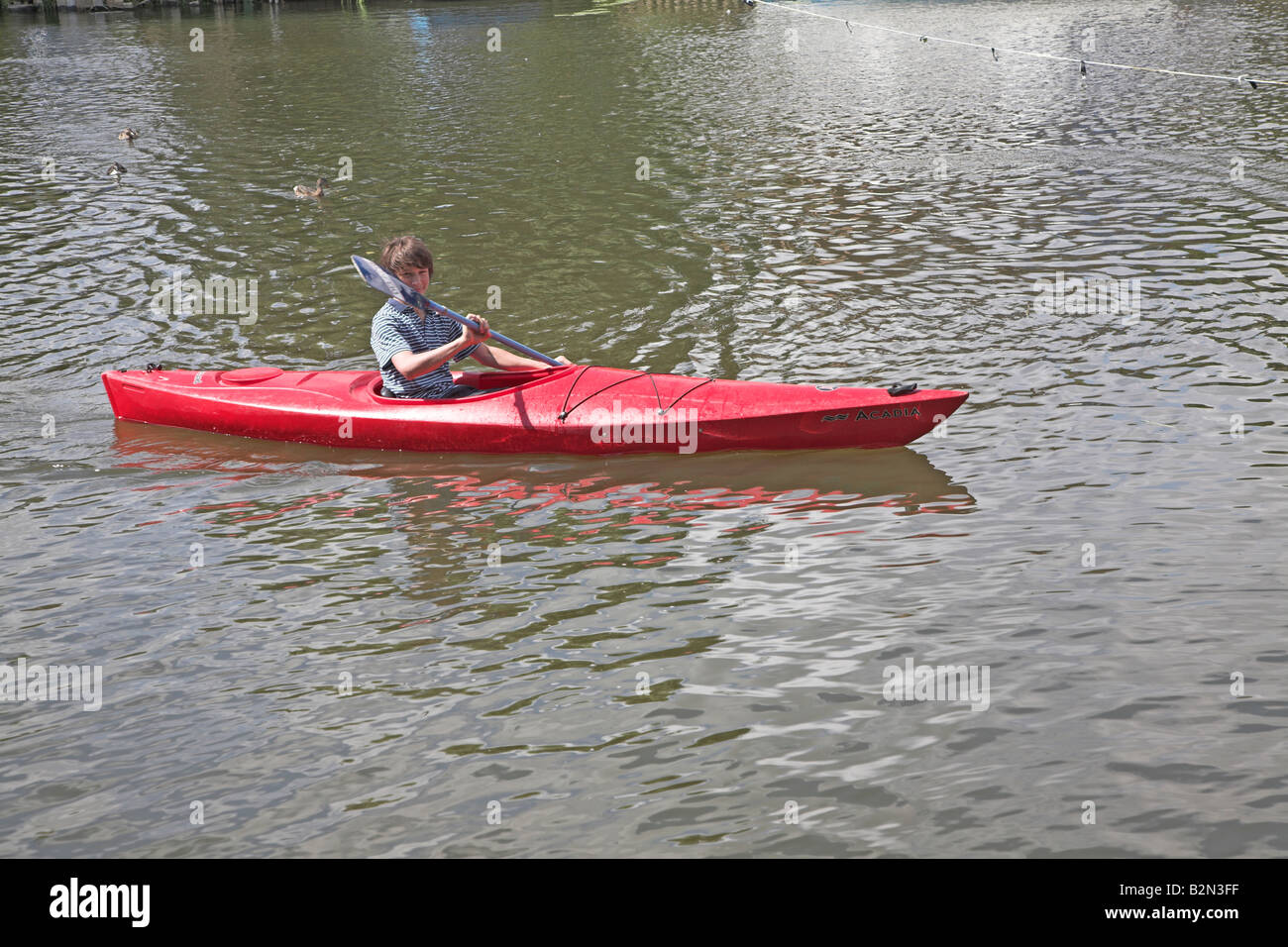 Boy paddling red kayak canoe Stock Photo - Alamy