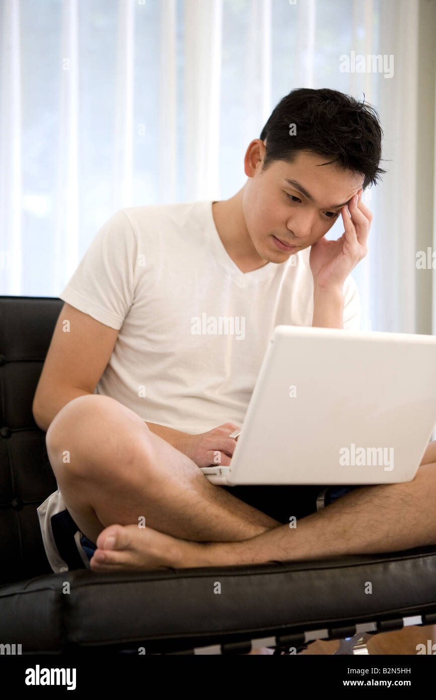 An exhausted young man using a laptop Stock Photo - Alamy