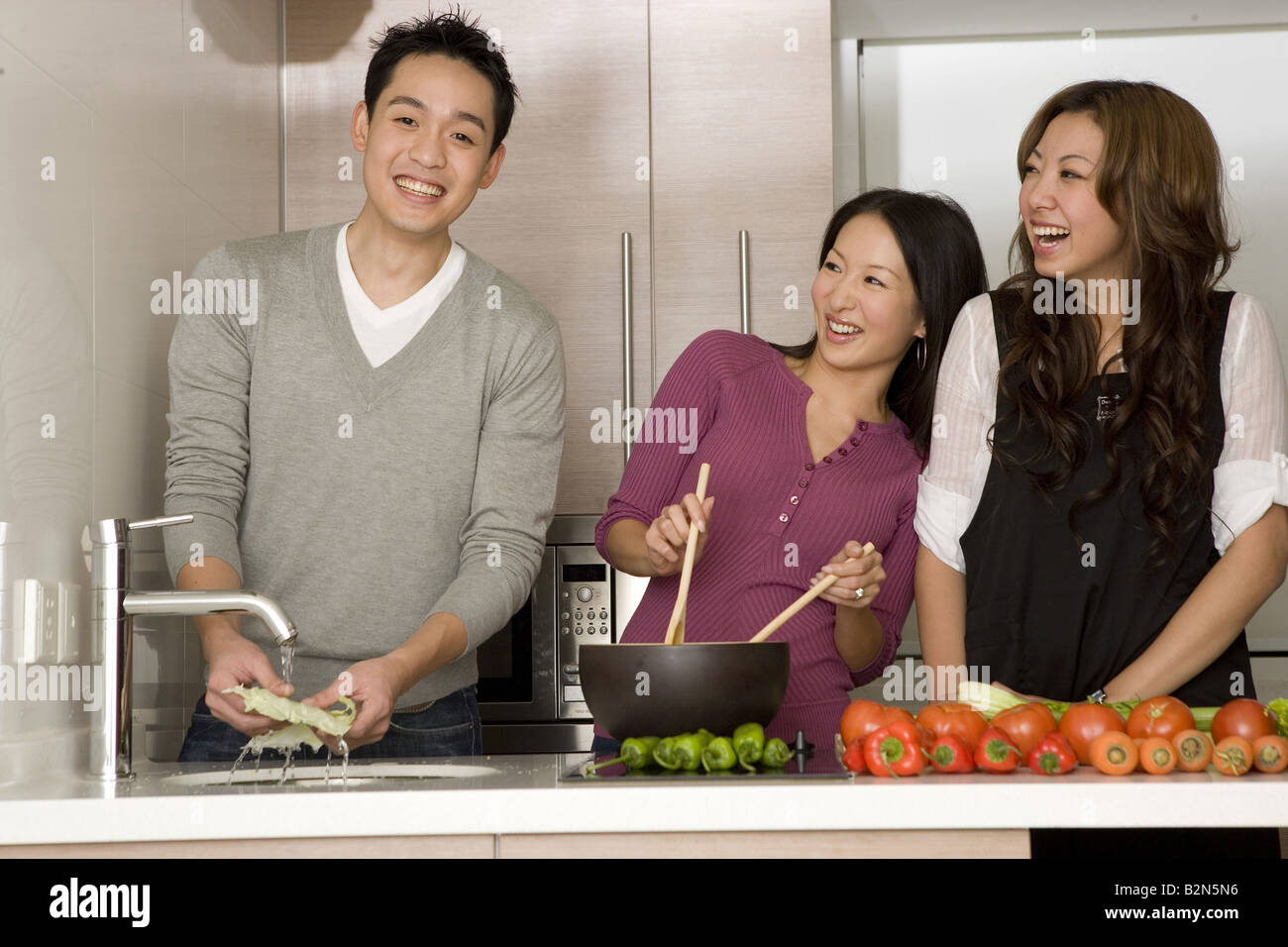 View of friends laughing while preparing dinner in a kitchen Stock ...