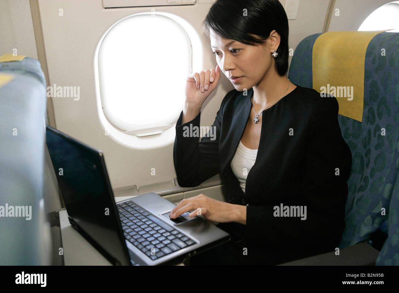 Businesswoman using a laptop in an airplane Stock Photo - Alamy