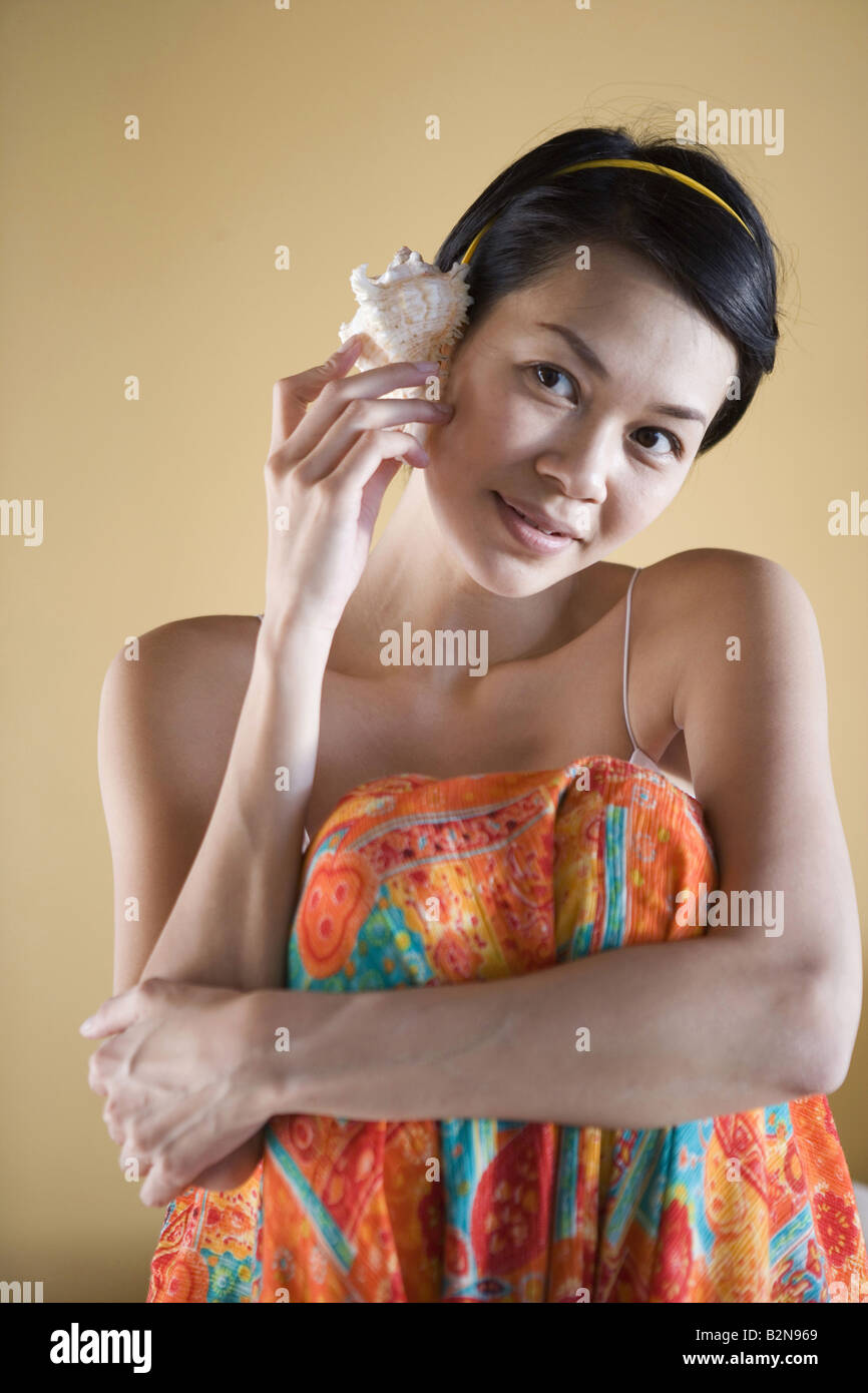 Woman holding seashell to ear hi-res stock photography and images - Alamy